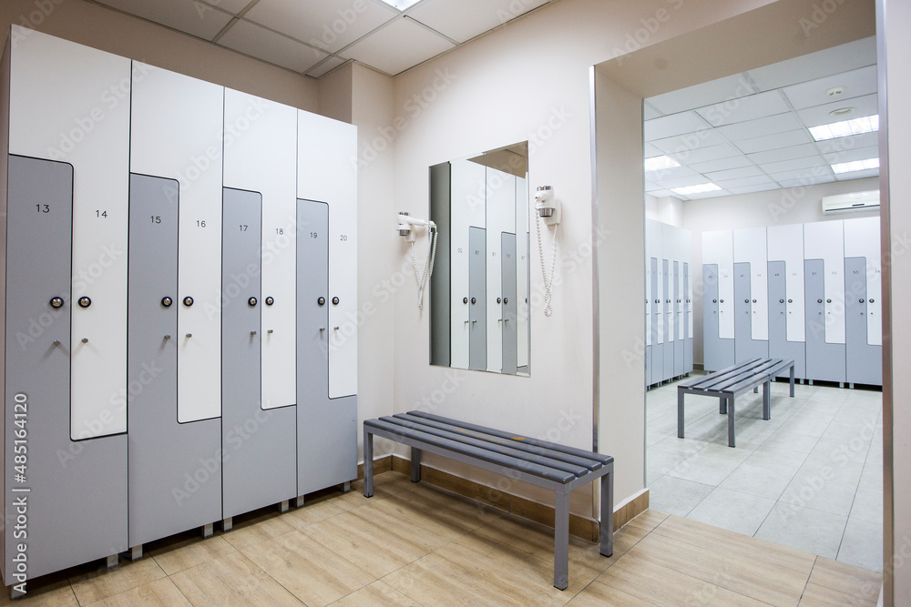 wide frame with a white locker room with wooden cabinets and benches ...