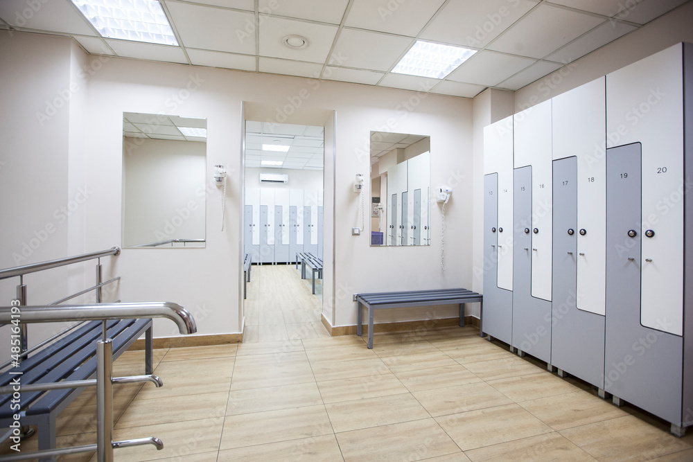 wide frame with a white locker room with wooden cabinets and benches ...