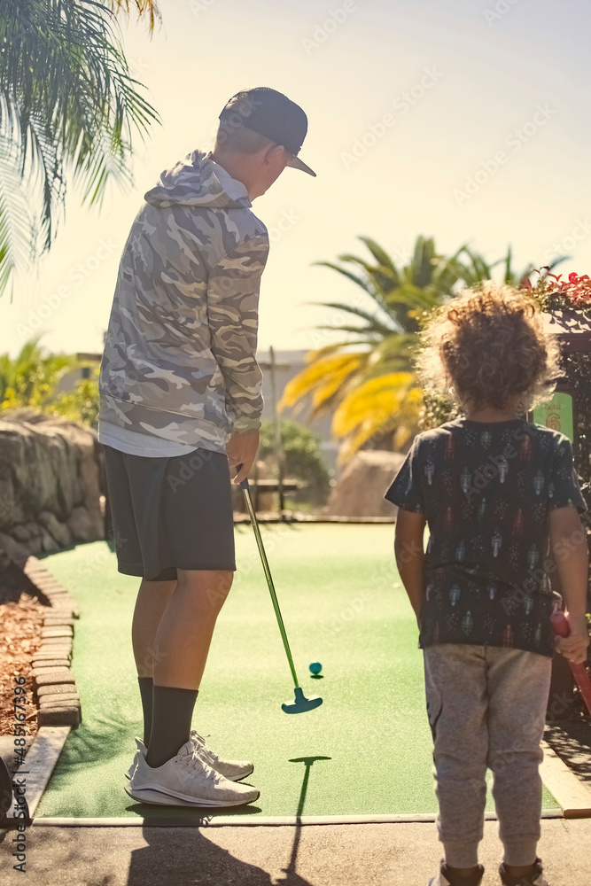 Rear view photo of two boys playing mini golf while on a fun family ...