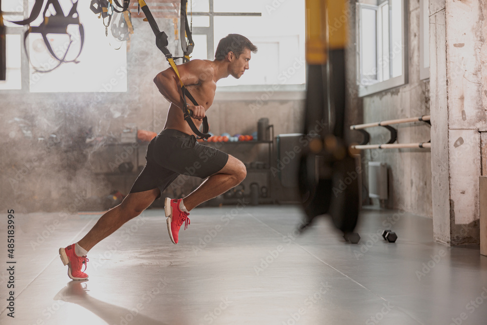 Side view of athlete sporty man doing exercise with fitness straps to ...