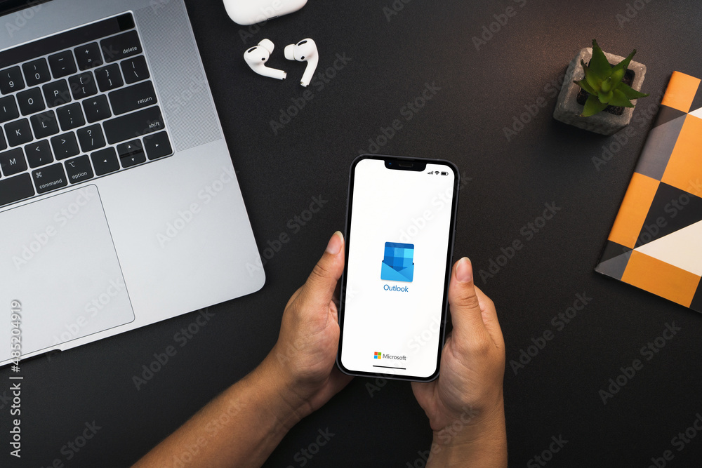 Girl holding a smartphone with Microsoft Outlook app on the screen on ...