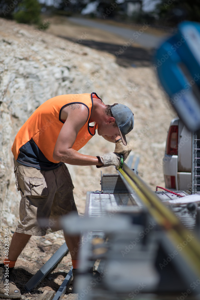 Tradie measuring metal frame on construction site Stock Photo | Adobe Stock
