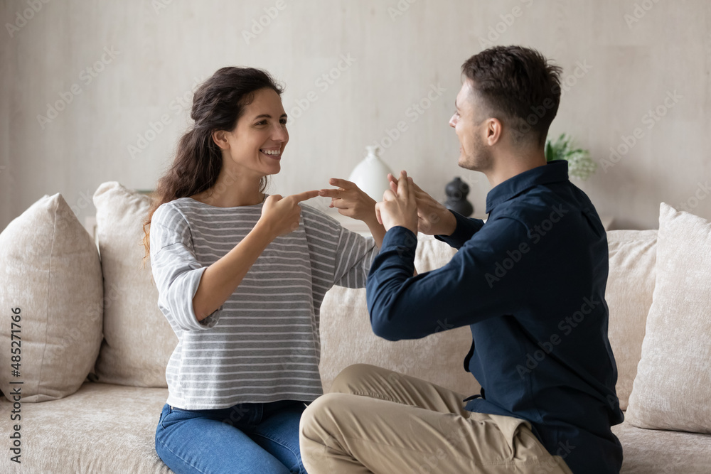 Smiling young woman who is deaf and man using sign language, sitting on ...