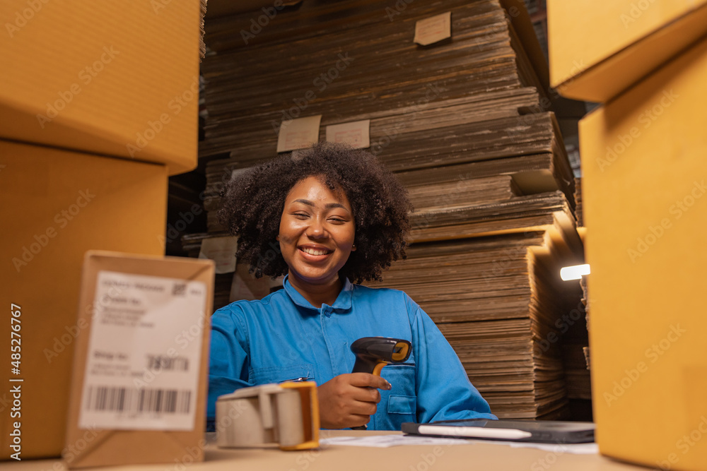 African American worker working in storage, taking parcel and scanning ...