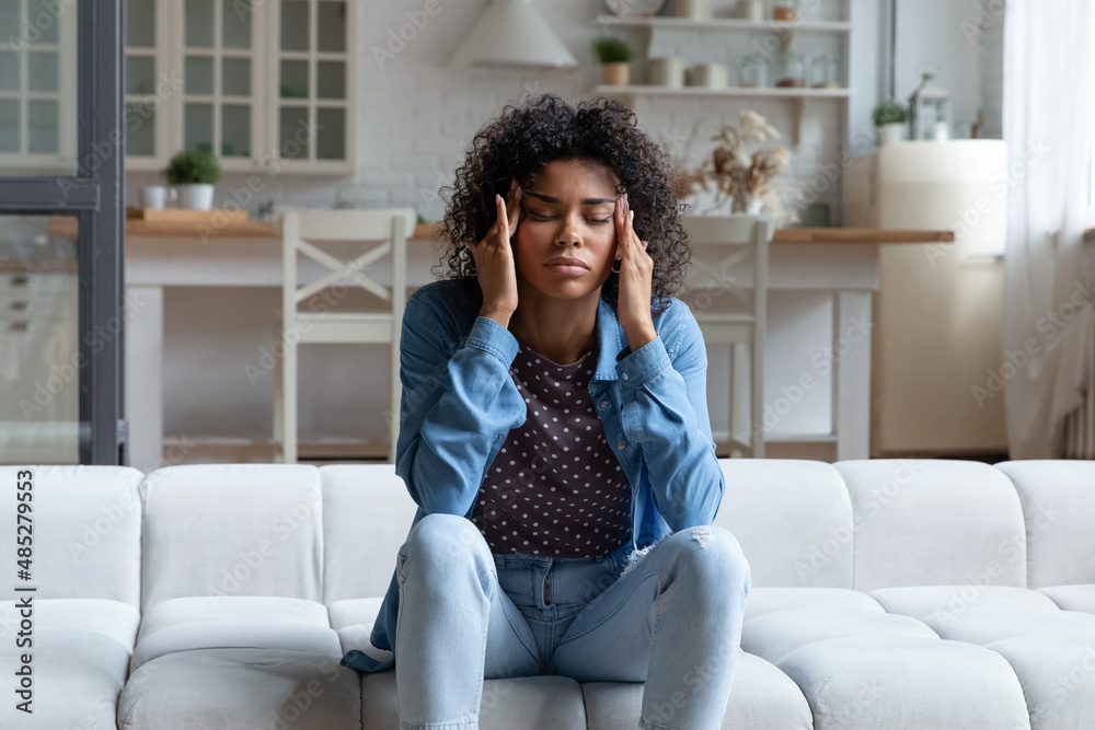Unhappy stressed young African American woman massaging temples ...