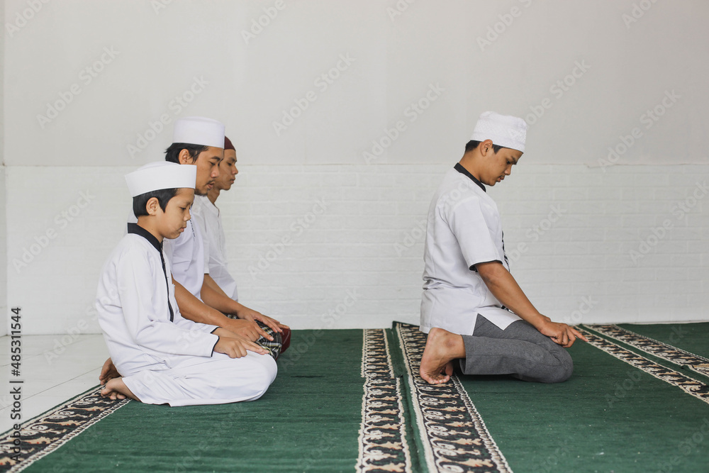 Side view of a group of Muslims praying in congregation with hand ...
