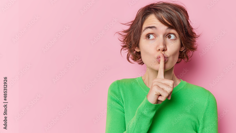 Beautiful young woman with bob hairstyle makes hush gesture shows ...