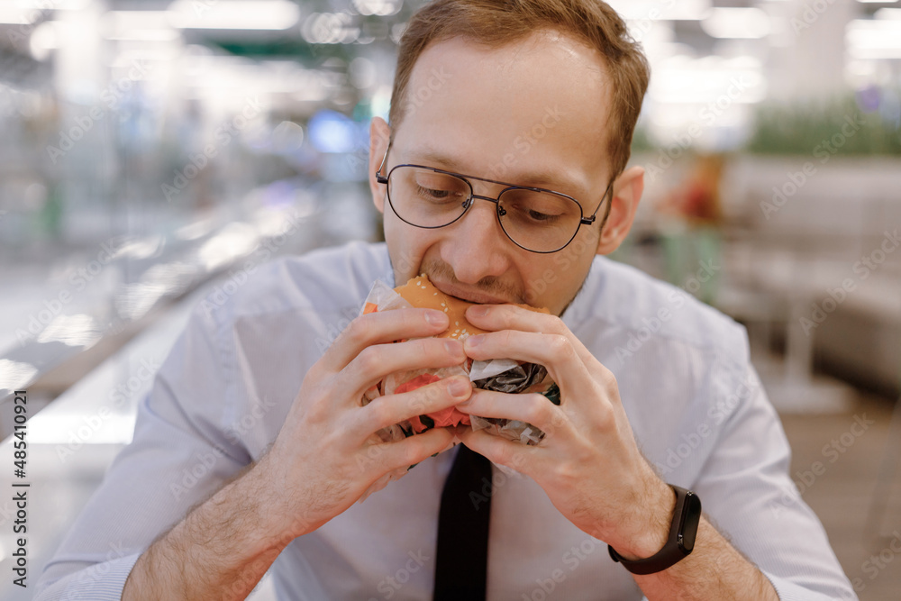 Office worker eating fast food burger and drink soda at food court in ...