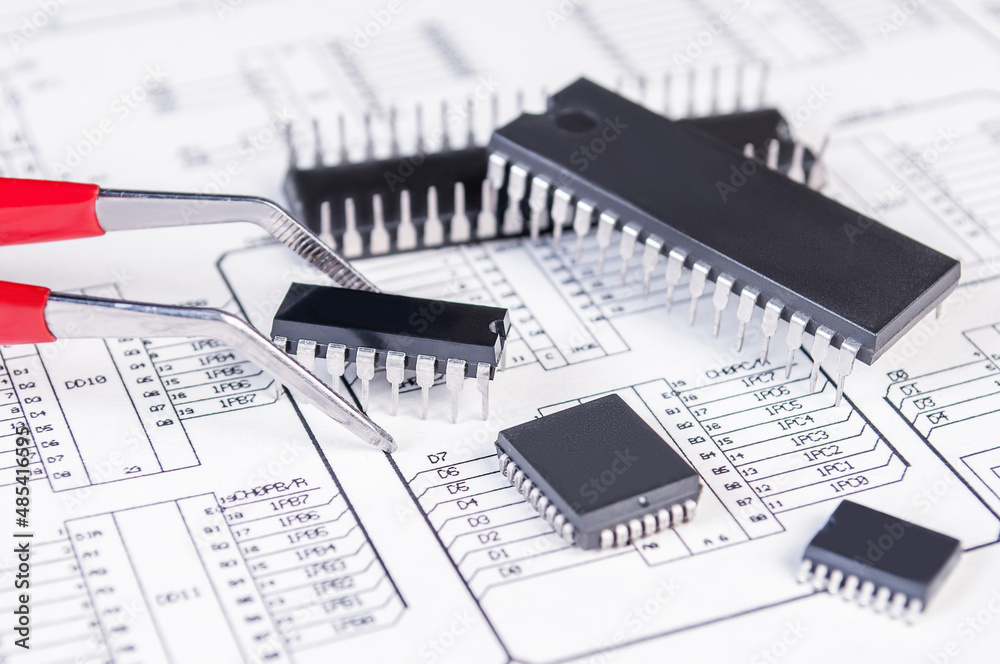 Electronics components and tweezers on background of schematic circuit ...