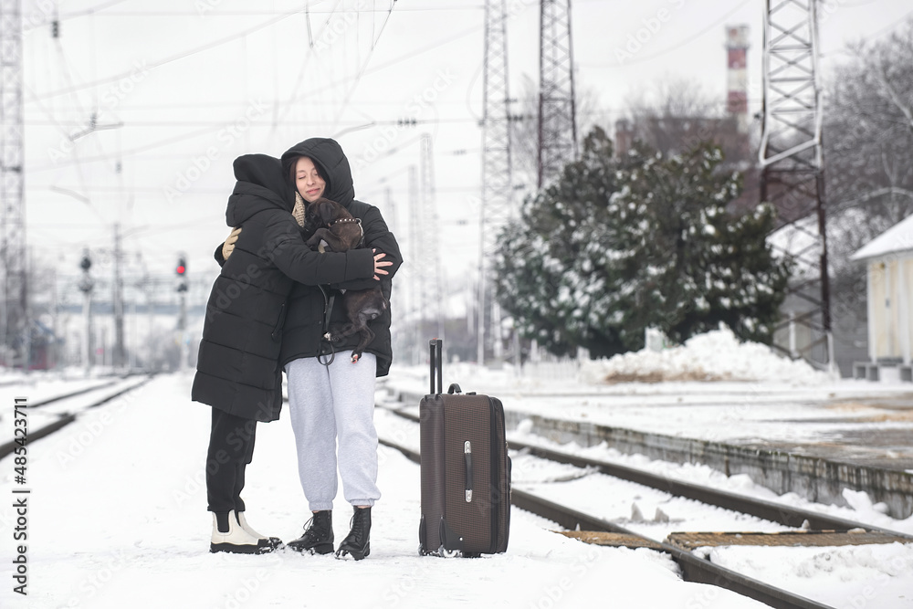 Meeting of happy girls on the platform of the railway station, they hug ...