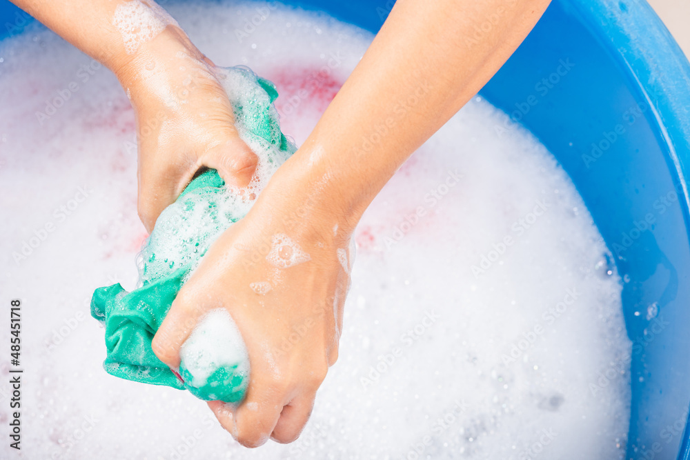 Closeup young Asian woman use hands washing color clothes in basin ...