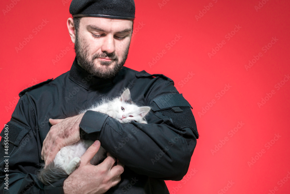 A male security guard in a black uniform and a cap holds a cute fluffy ...