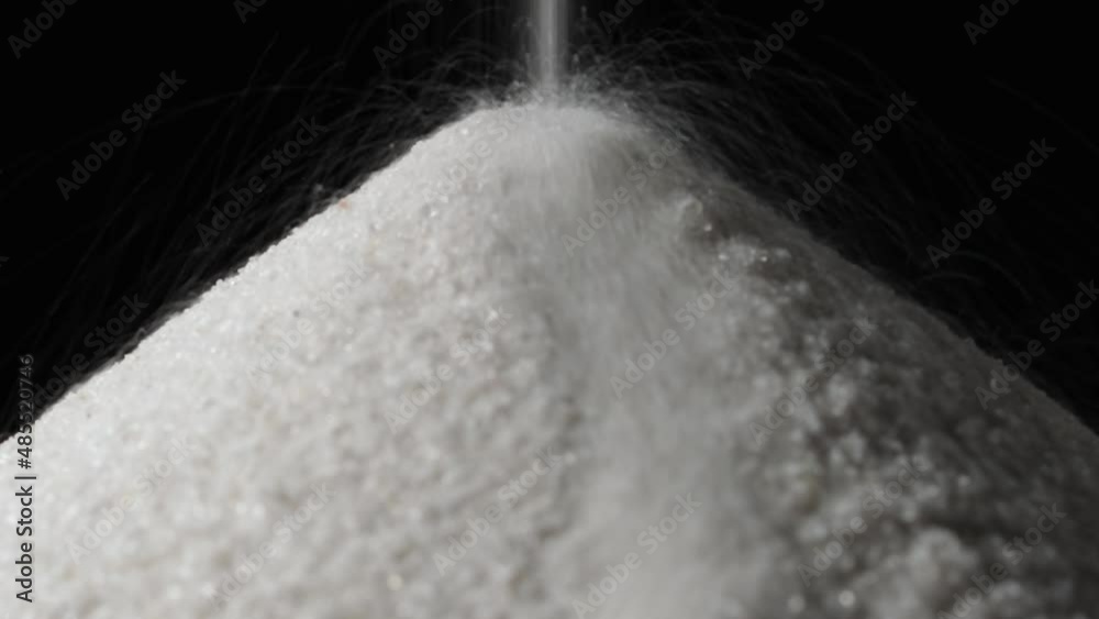 Particles of white dry sand are pouring down forming hill on an ...