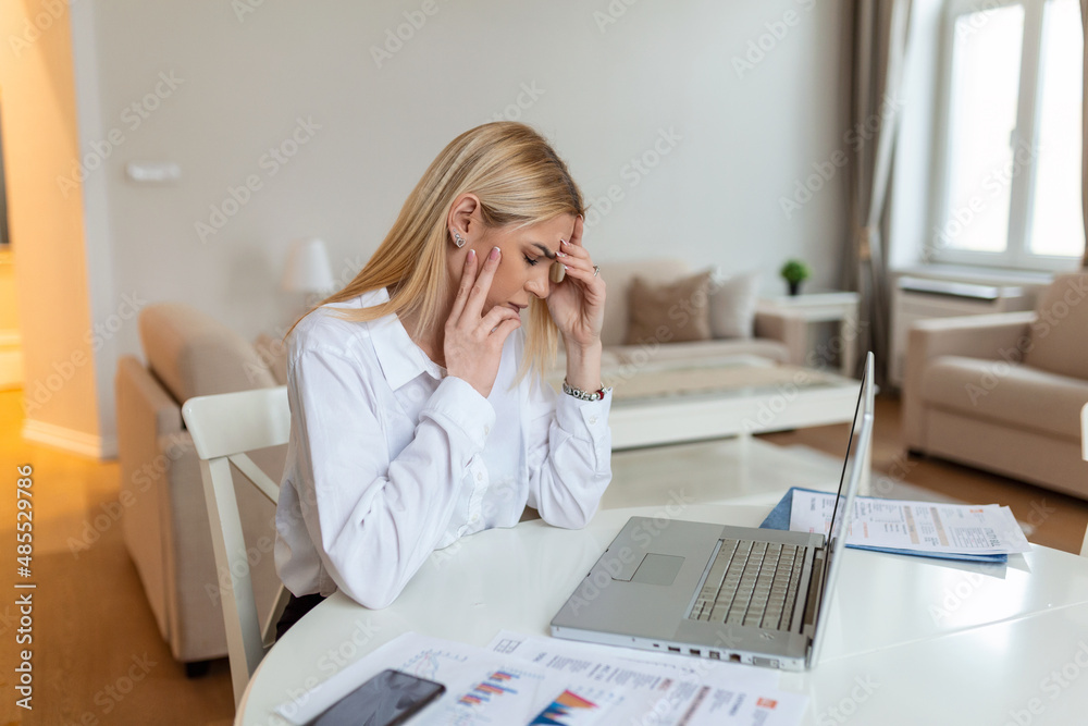 Young frustrated woman working at office desk in front of laptop ...