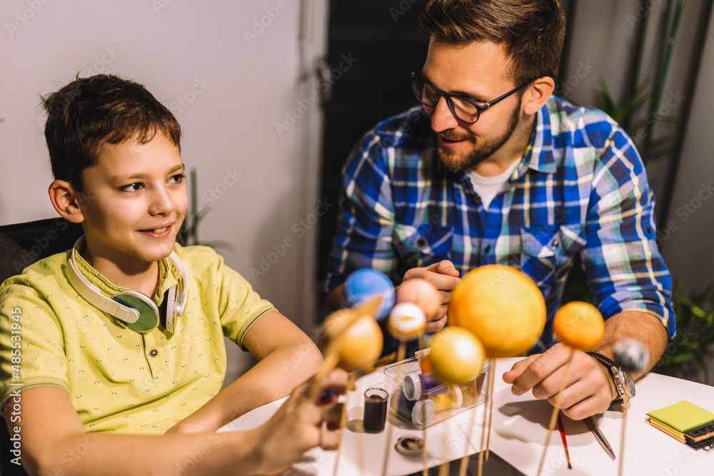 Happy school boy and his father making a solar system for a school ...
