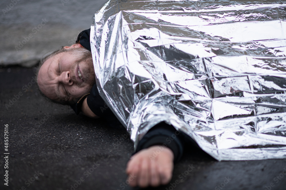 Unconscious man in medical shock lying under emergency blanket Stock ...