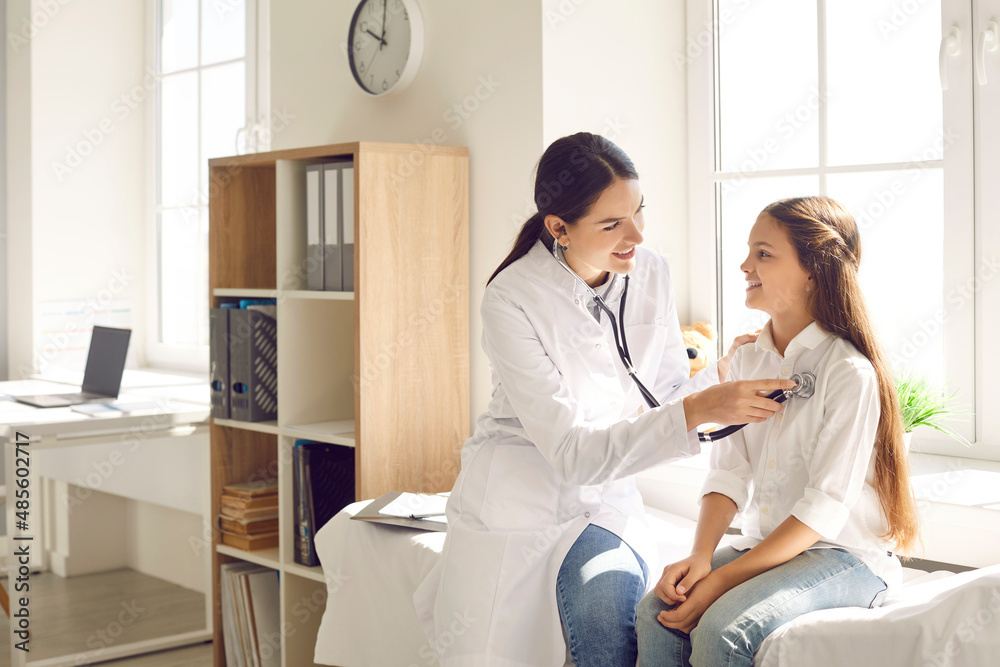 Smiling doctor checking child's lungs during medical checkup in modern ...