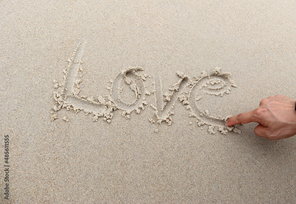 Young man hand writing word love in cursive on sand beach Beach love ...
