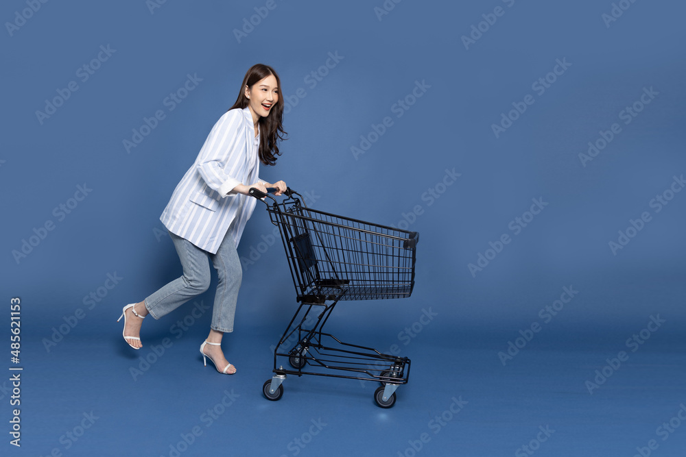 Full length portrait of young Asian woman pushing an empty shopping ...