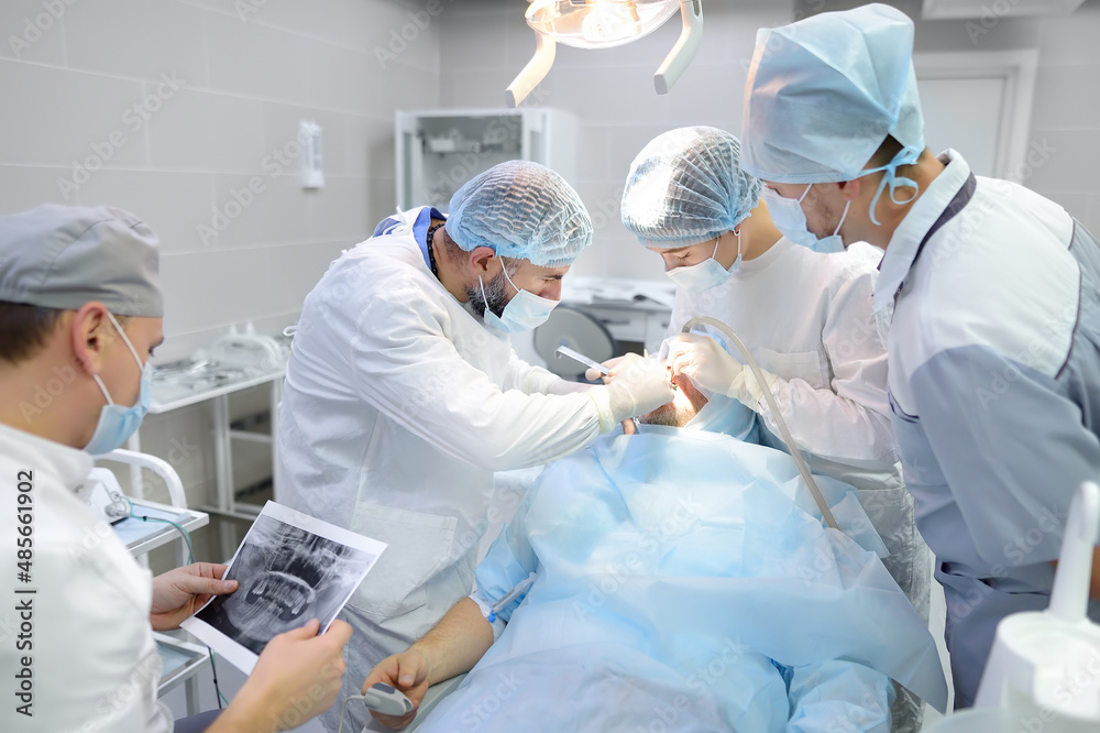 Surgeons and nurse during a dental operation. Medical team performing ...