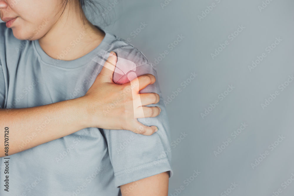 Health concept, person has left shoulder pain, woman uses right hand to ...