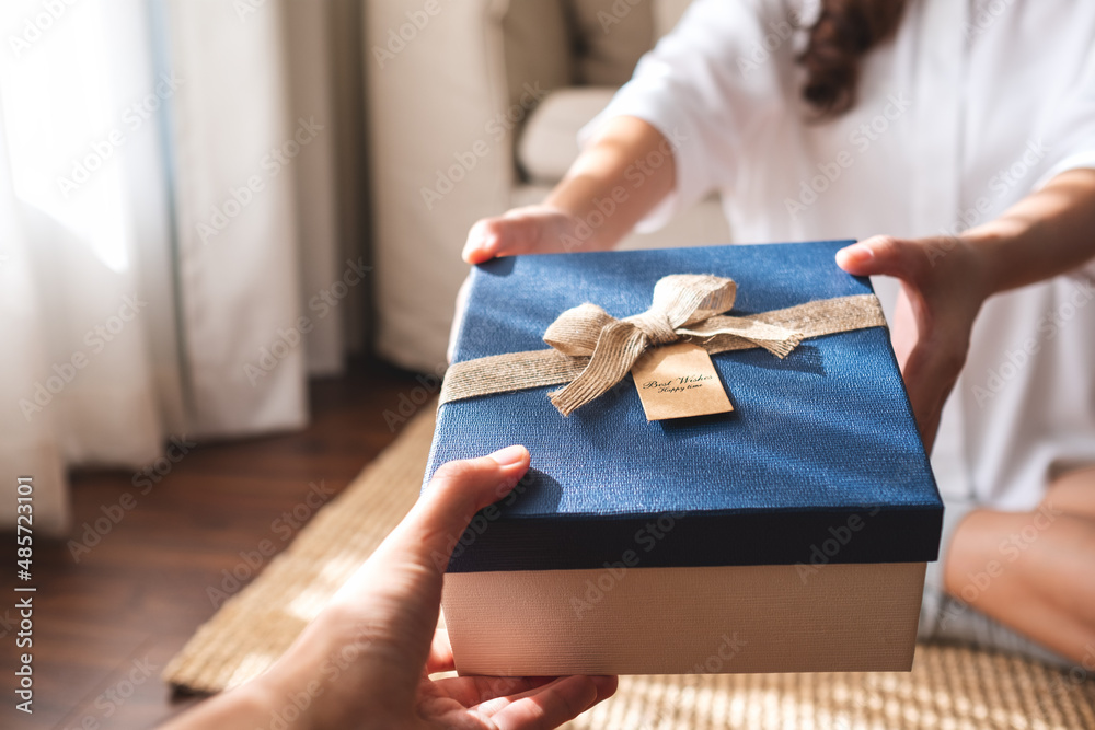 Closeup image of a young couple giving and receiving a gift box to each ...