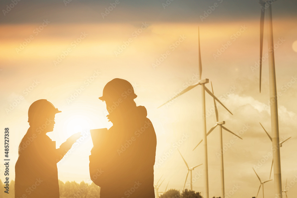 Silhouette of Engineers checking project at wind turbine site on sunset ...