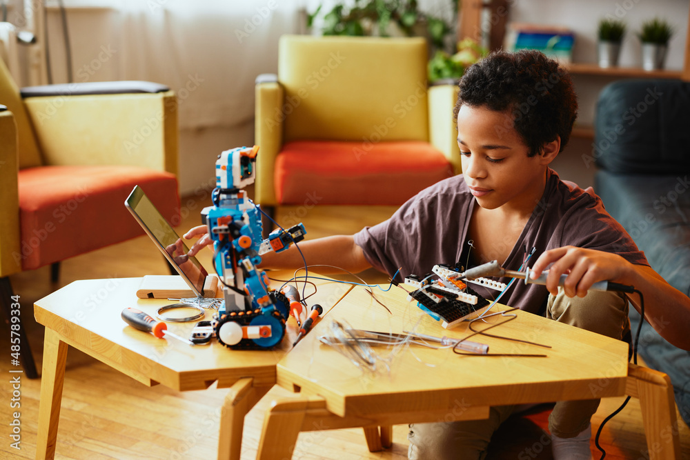 An African-American boy making a robot at home. Education in robotic at ...