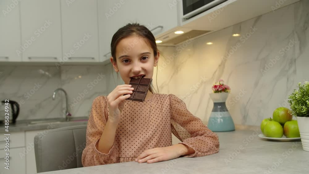 Cute preteen girl biting piece of chocolate, rejoicing taste of sweet ...