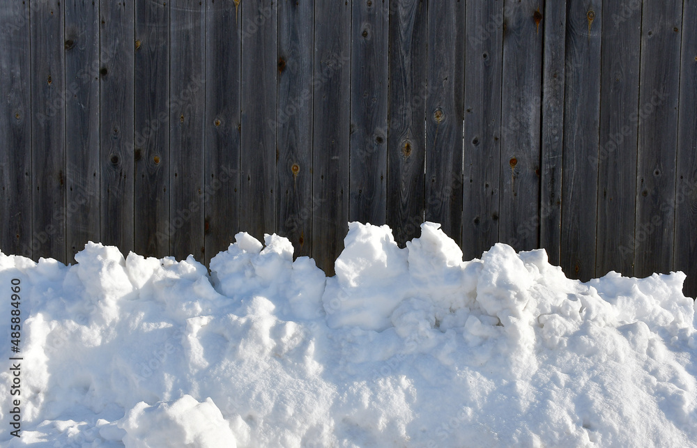 Winter background. A snowdrift on the background of an old fence made ...