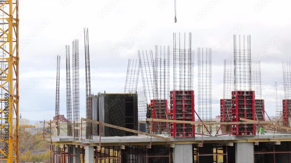 Workers build a high-rise building of reinforced concrete, pouring ...