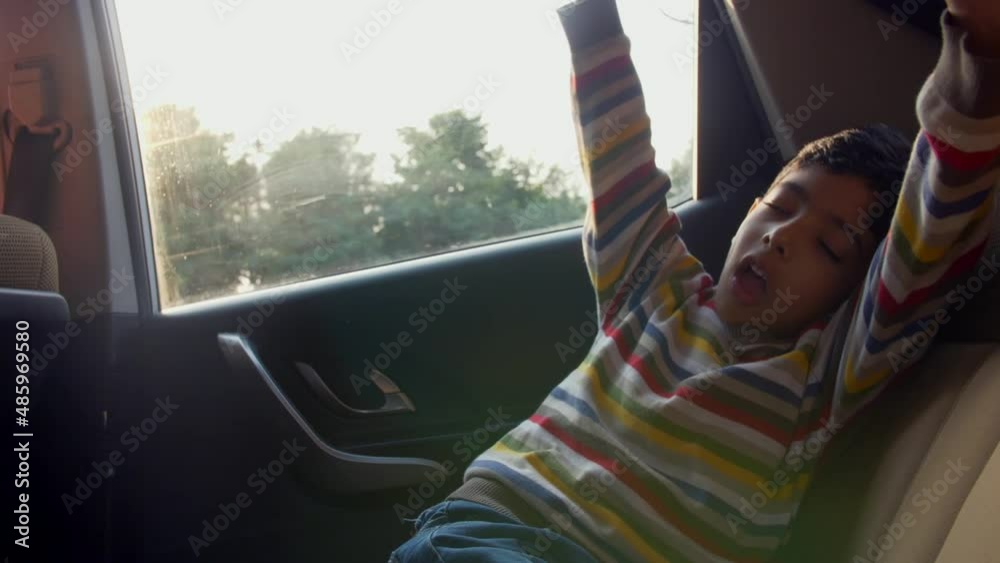 A tired little kid sleeping / resting in the back seat of his car while ...