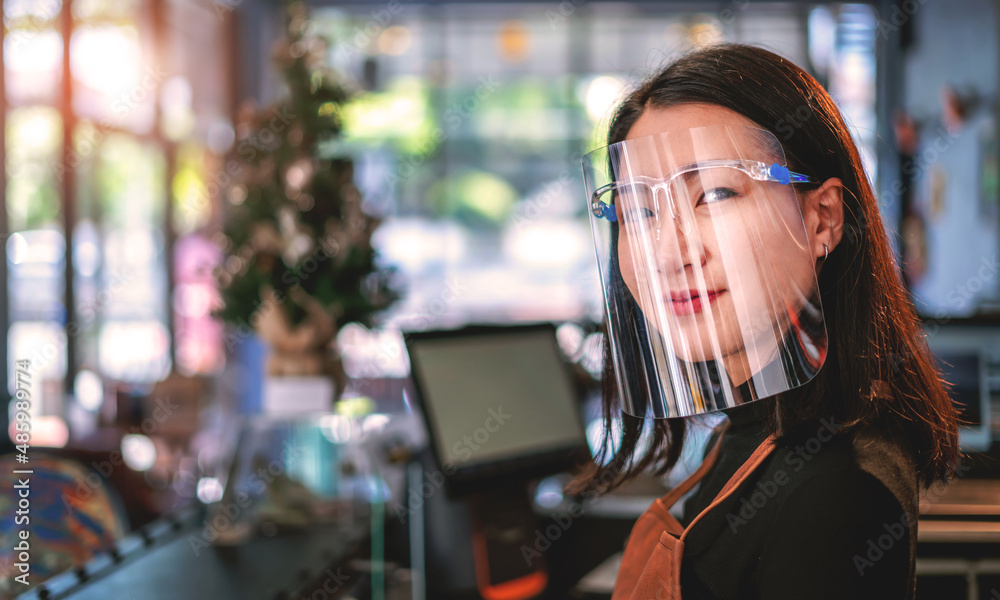 Young Asian adult owner gen z woman is wearing protective face shield ...
