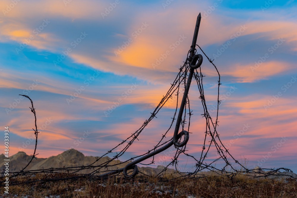 Barbed wire fence beneath colorful sky. These ruins are part of "Vallo ...