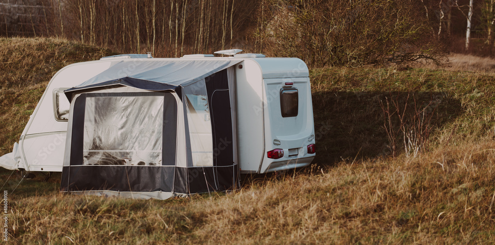 Caravan trailer parked on a green lawn in a small village on a clear ...