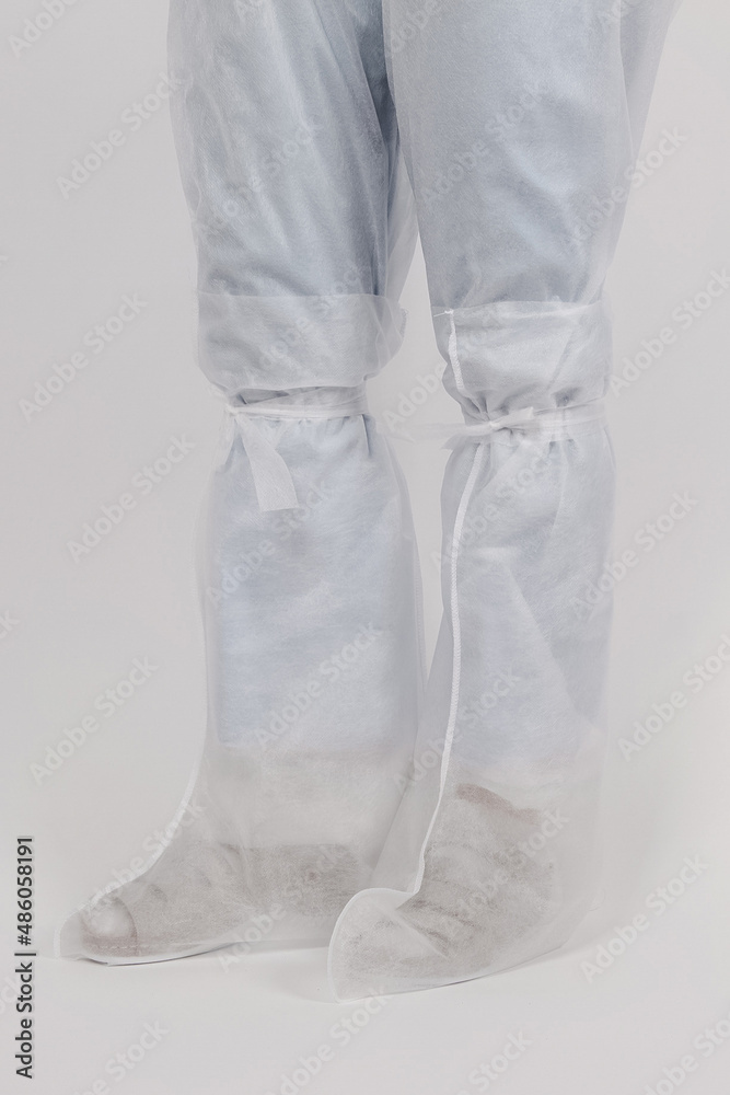 Nurse wears disposable gown and disposable shoes cover. Doctor putting ...