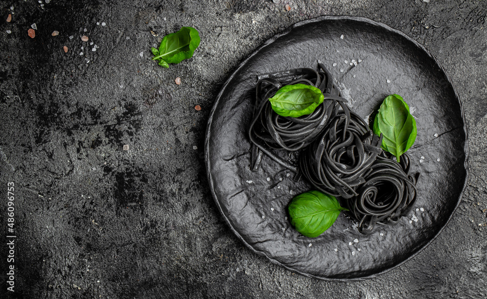 black pasta with cuttlefish ink and green basil leaves. Pasta of durum ...