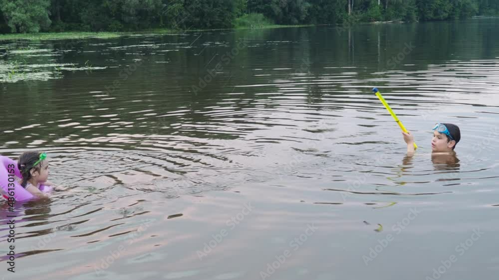 happy children, boy and girl swim in a forest lake. splashing each ...