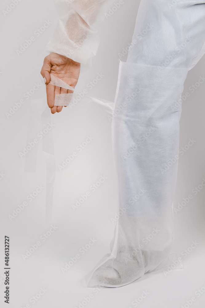 Nurse wears disposable gown and disposable shoes cover. Doctor putting ...