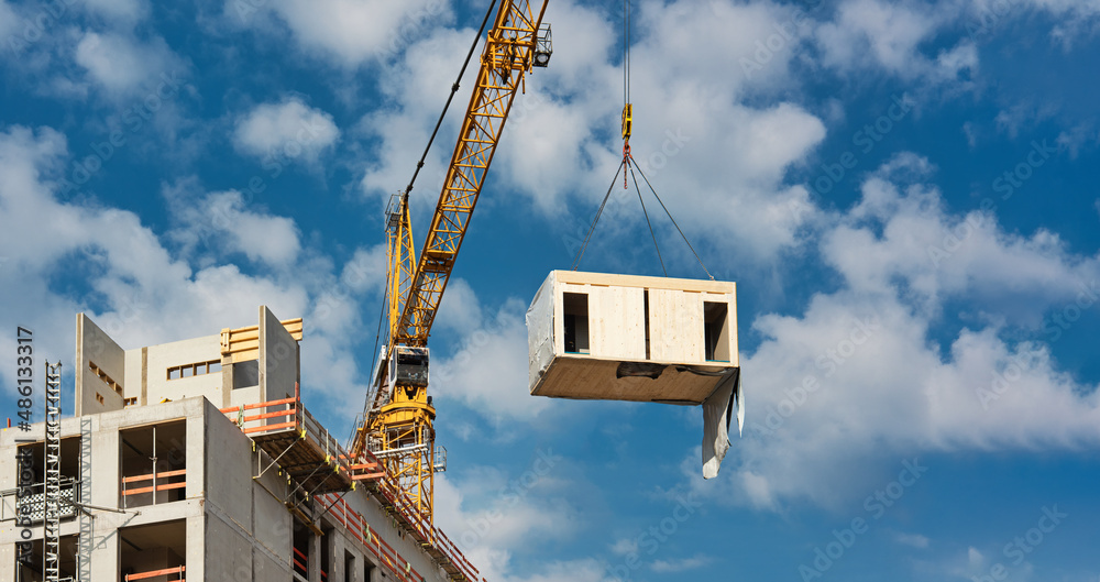 A Crane is lifting a wooden building module to its position in the ...