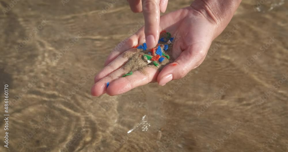 Plastic pollution in wildlife. A girl show her hands with sand and ...