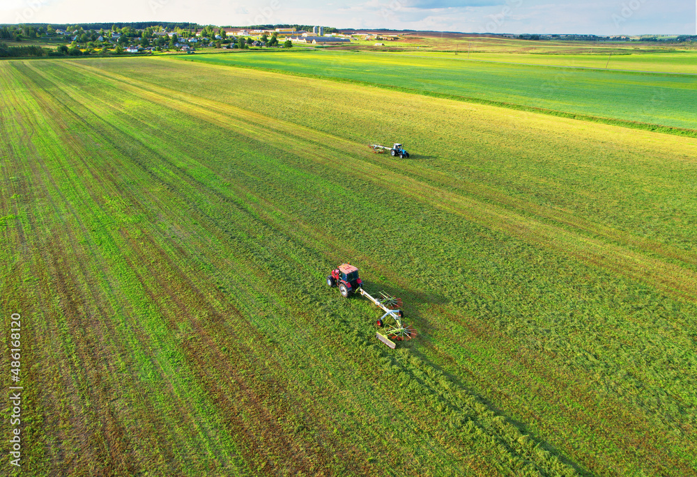 Tractor raking grass for silage harvesting. Agriculture farm machinery ...