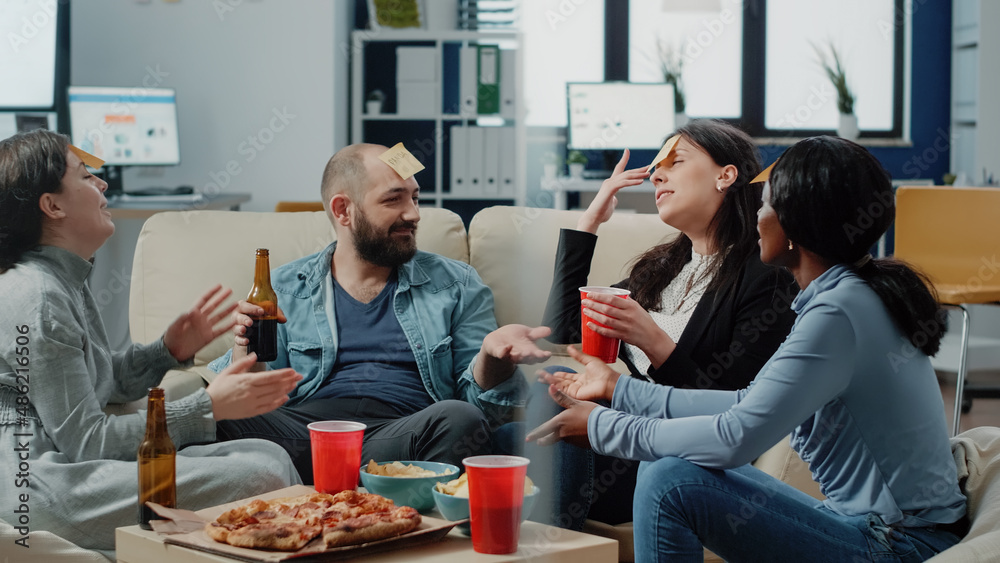 Diverse group of workmates playing charades with sticky notes on ...