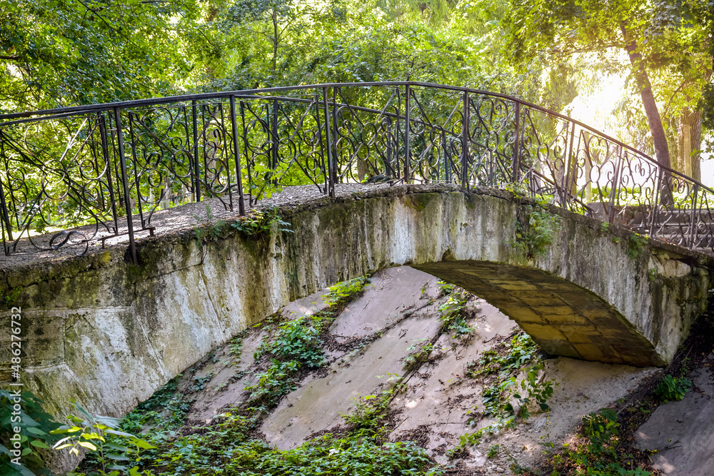Old concrete arched footbridge with wrought iron railings against ...