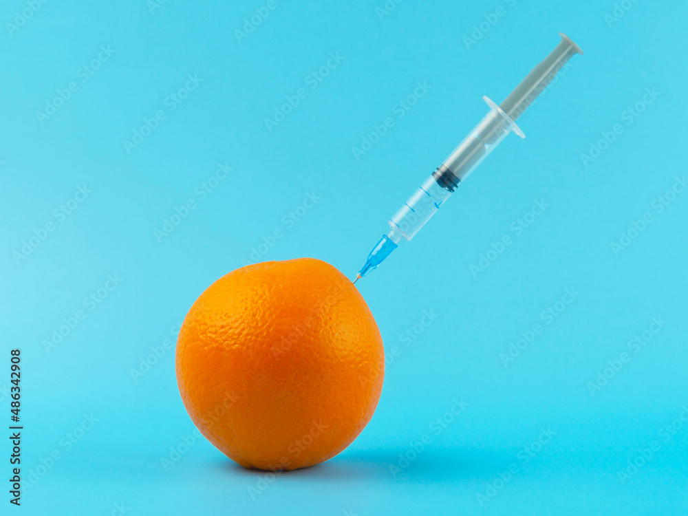 Orange orange with an inserted syringe on a blue background. Orange ...