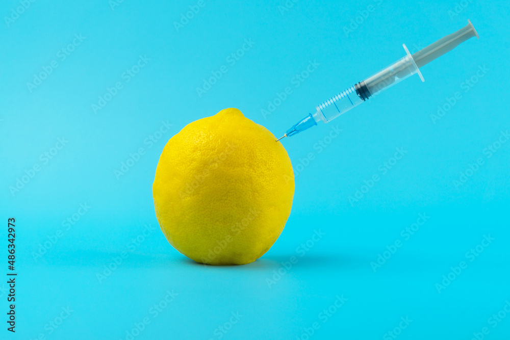 Yellow lemon with inserted syringe on a blue background. Lemon ...