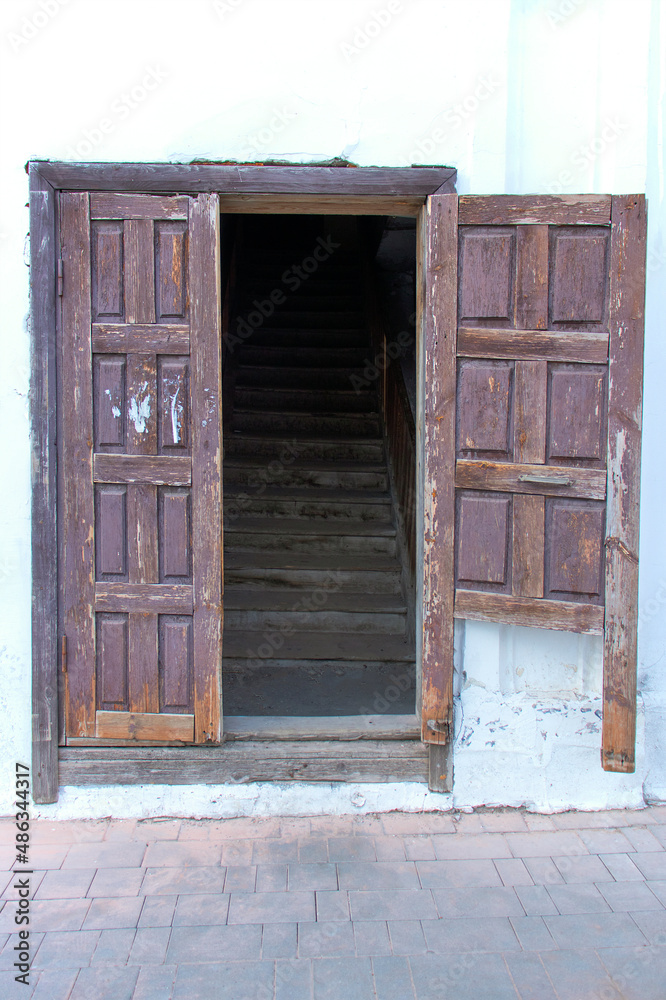 The entrance to an old dilapidated entrance with a broken wooden door. White walls. A wooden ...
