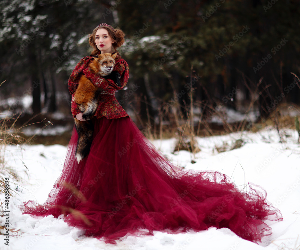 Beautiful young woman in red traditional dress with red fox on hands in ...