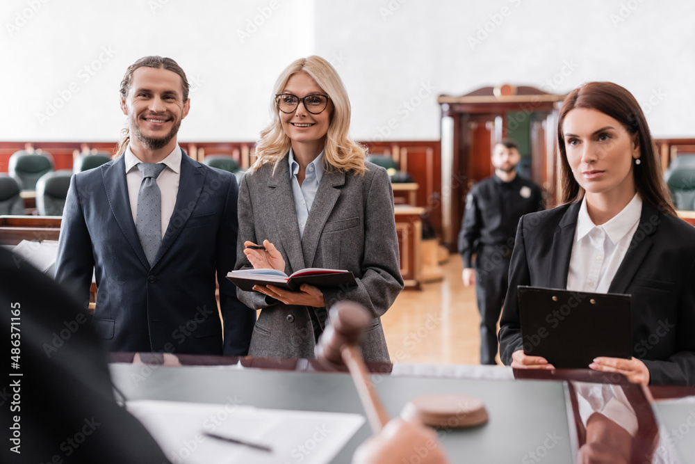 smiling advocate pointing with hand near happy businessman and judge on ...