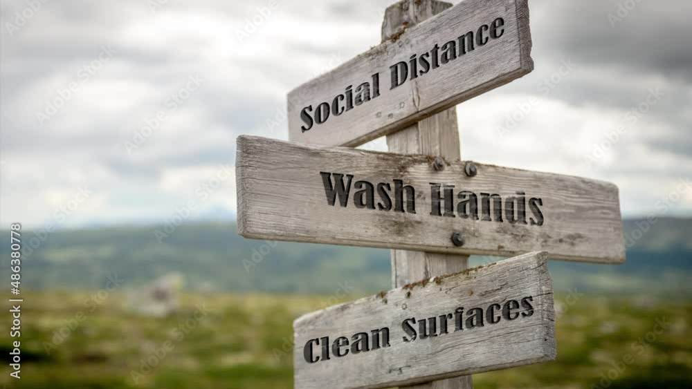 Signpost outdoors with the text social distance, wash hands and clean ...